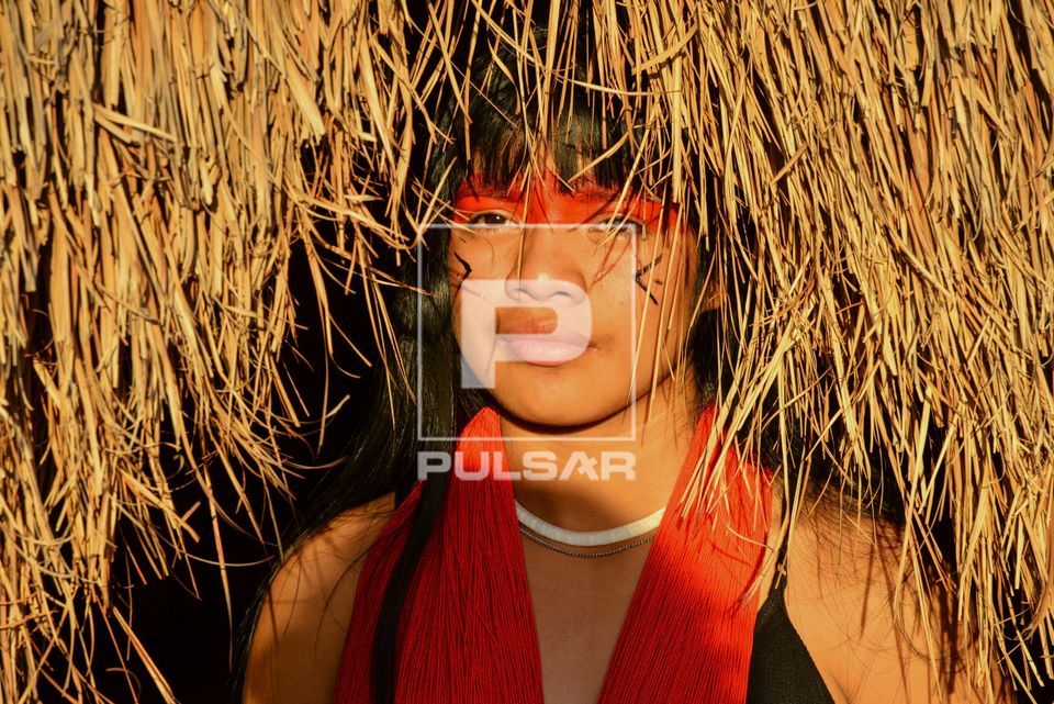 Indígena kuikuro da aldeia Ipatse com colares posando na entrada da oca ...