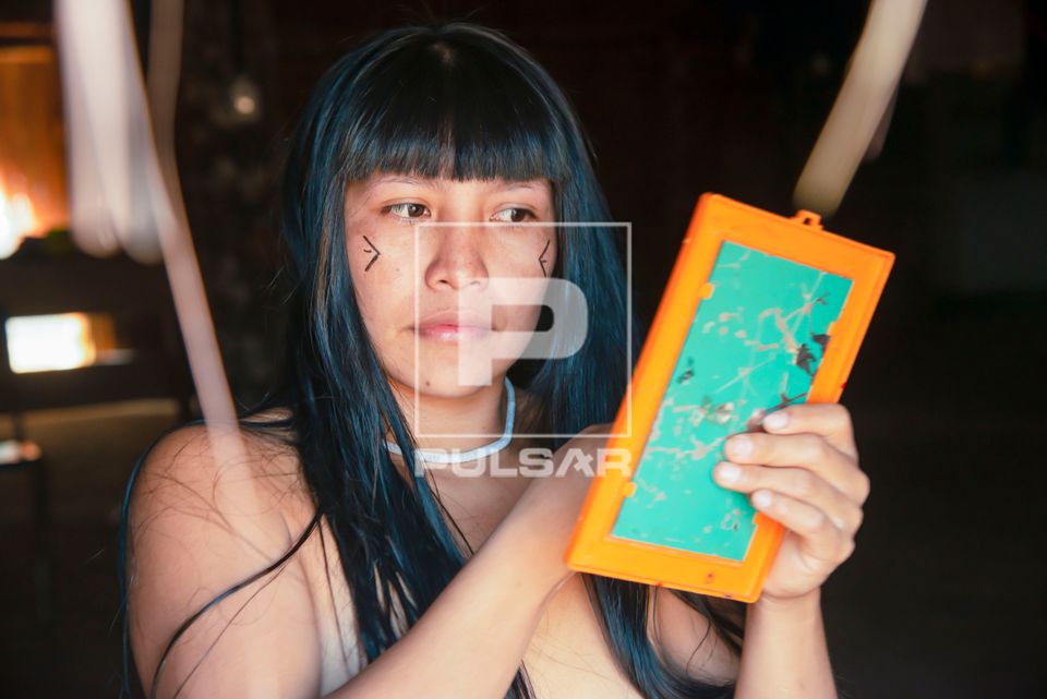 Mulher indígena da etnia Kalapalo fazendo pintura corporal com auxílio ...