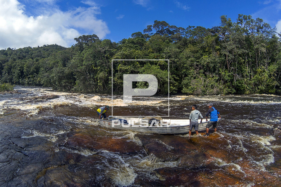 Índios da etnia Ingarikó empurram barco em corredeira do Rio Cotingo na ...