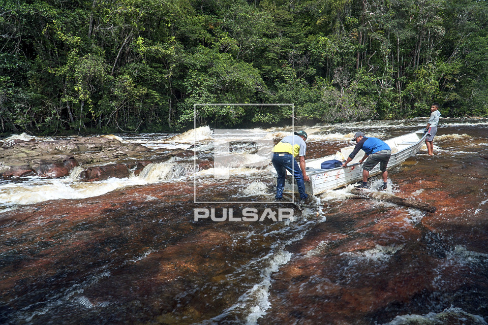 Índios da etnia Ingarikó empurram barco em corredeira do Rio Cotingo na ...