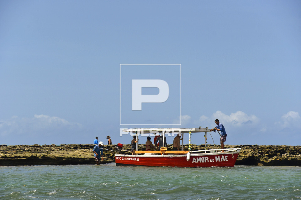 Barco ancorado durante passeio turístico no arrecife de corais da praia ...