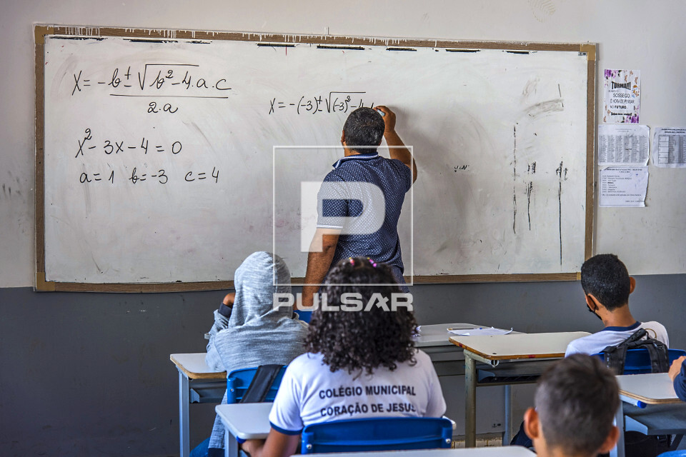 Professor escrevendo na lousa fórmula de Bhaskara durante aula de ...