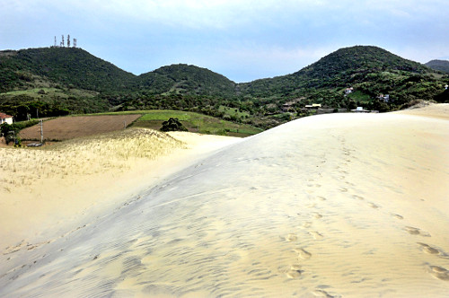 Lagoa em meio as dunas e vegetação com mar ao fundo na Praia do Siriu ...