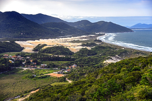 Lagoa em meio as dunas e vegetação com mar ao fundo na Praia do Siriu ...