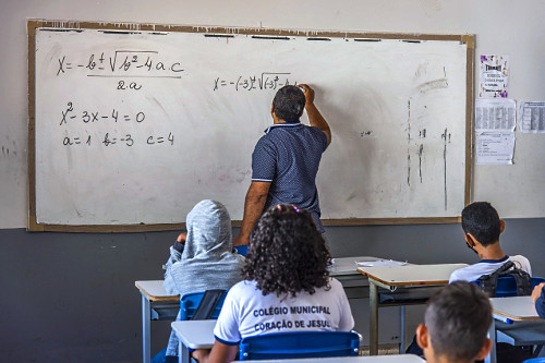 Professor escrevendo na lousa fórmula de Bhaskara durante aula de ...
